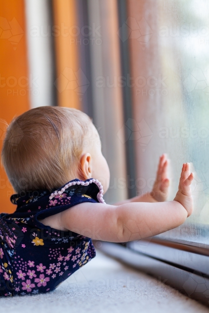 Image of Baby with hands up on window looking outside - Austockphoto