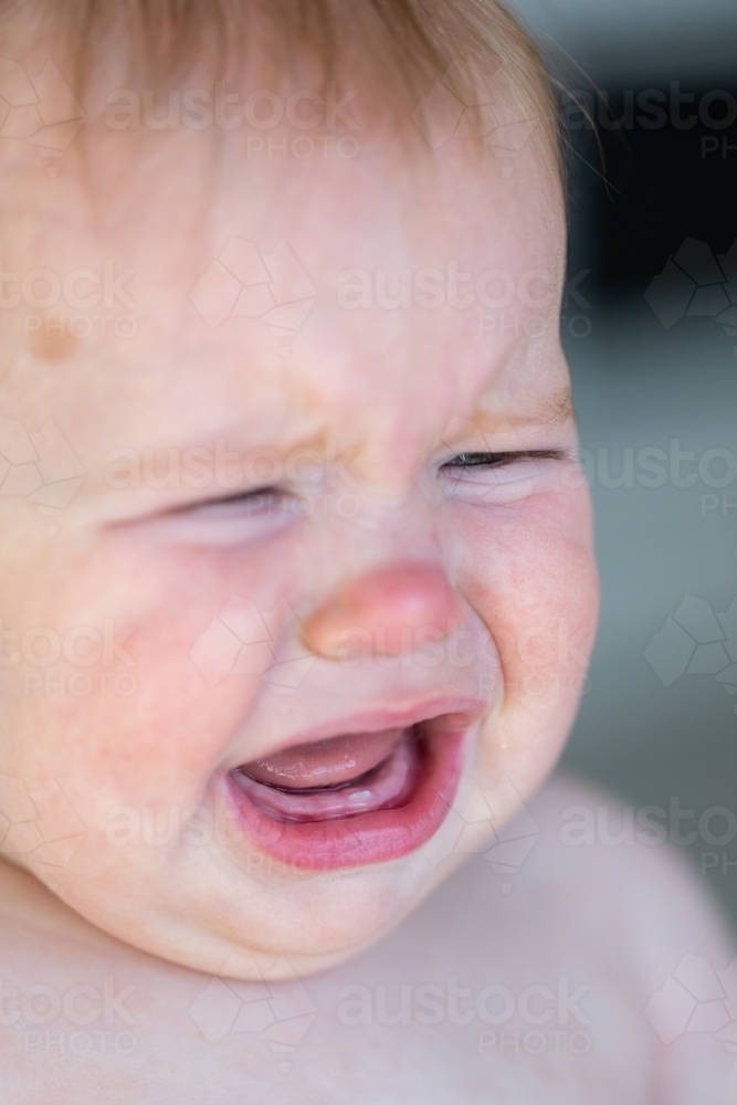 Image of Baby with new first tooth looking sad crying - Austockphoto
