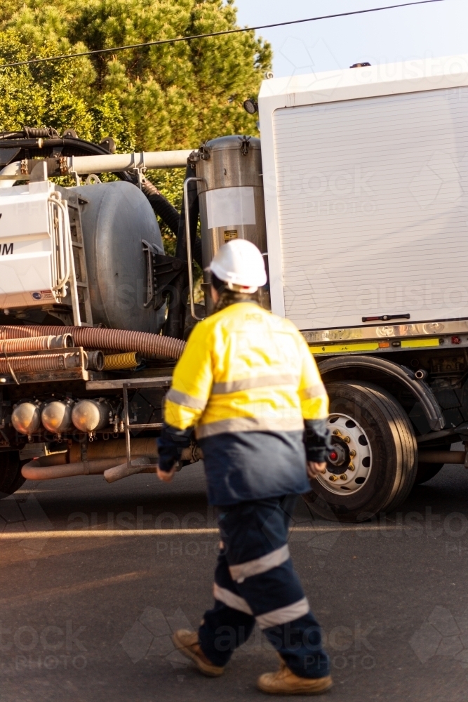 Image of Back shot of woman road worker wearing white helmet and yellow ...