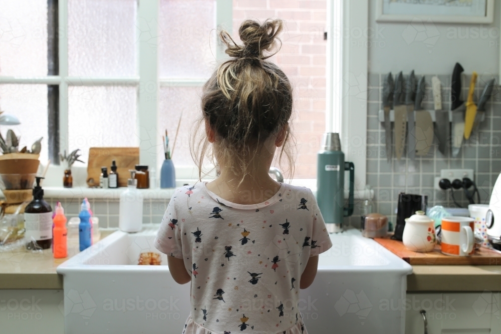 Image of Back view of a small girl with messy hair washing up at ...