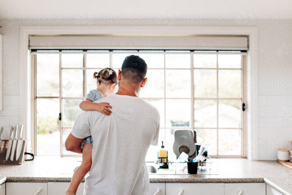Image of Back view of father carrying toddler daughter in the kitchen ...