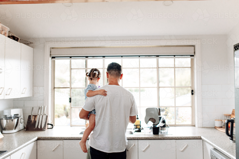 Image of Back view of father carrying toddler daughter in the kitchen ...