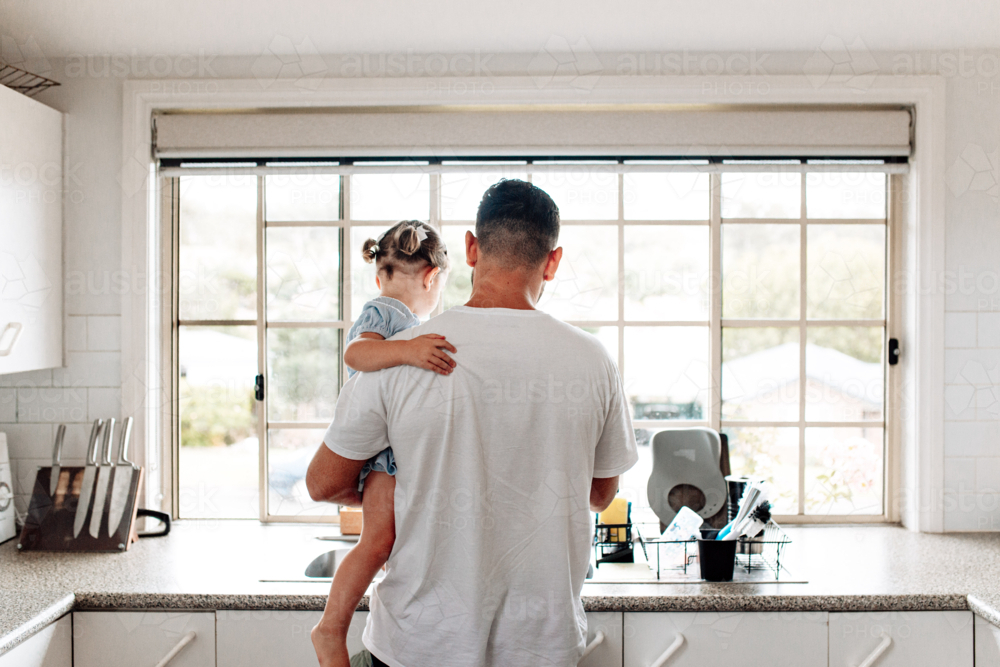 Image of Back view of father carrying toddler daughter in the kitchen ...