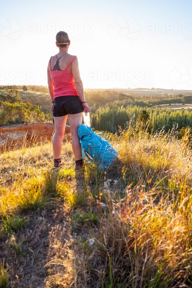 Image of Back view of female bushwalker standing on a hilltop admiring ...