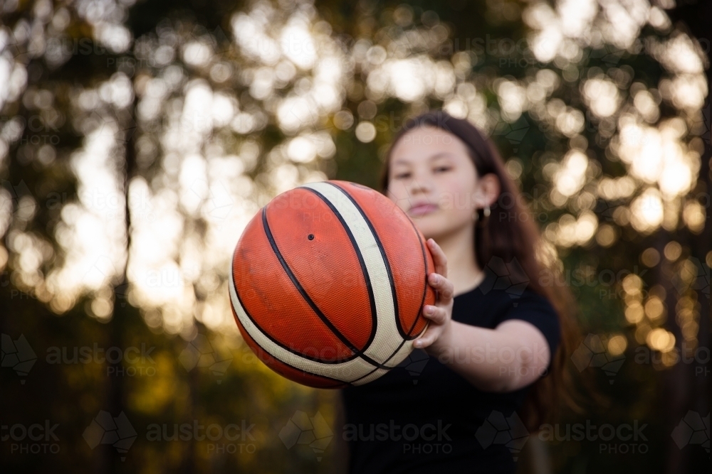 Image of basketball close up held out by teen girl - Austockphoto