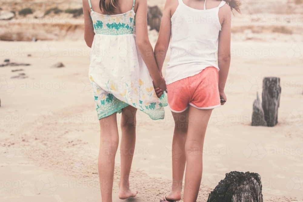 Image of Behind view of two girls walking along the beach holding hands ...