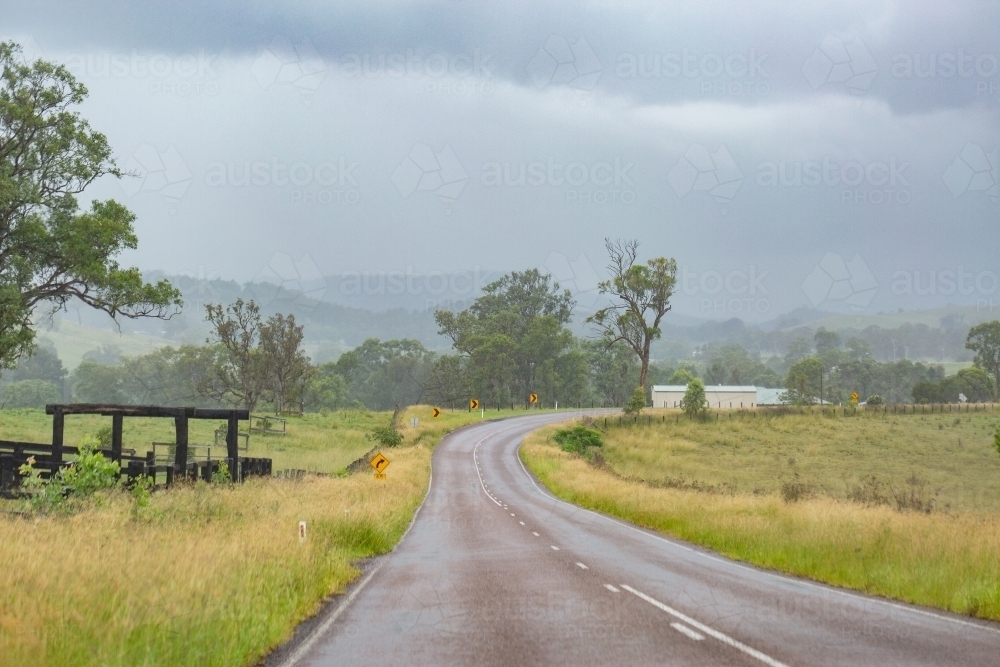 Image of Bend in slippery country road during rain - Austockphoto