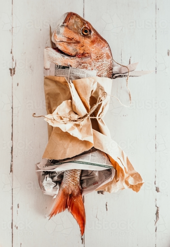Image of Big pink snapper fish wrapped in paper. - Austockphoto