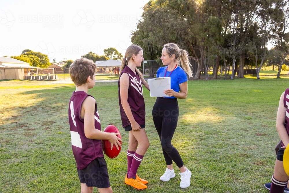 Image of blonde female adult coaching children at Aussie Rules football ...
