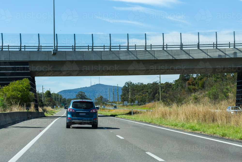 Image of blue car driving down divided highway with overpass ahead in ...