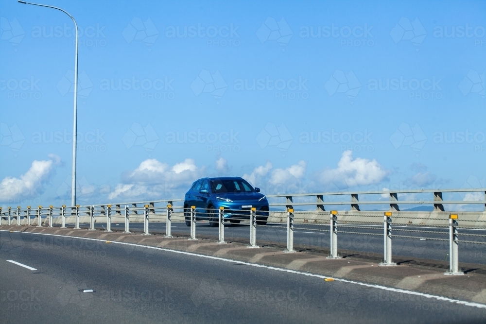 Image of Blue car on curving bridge with blue sky copy space - Austockphoto