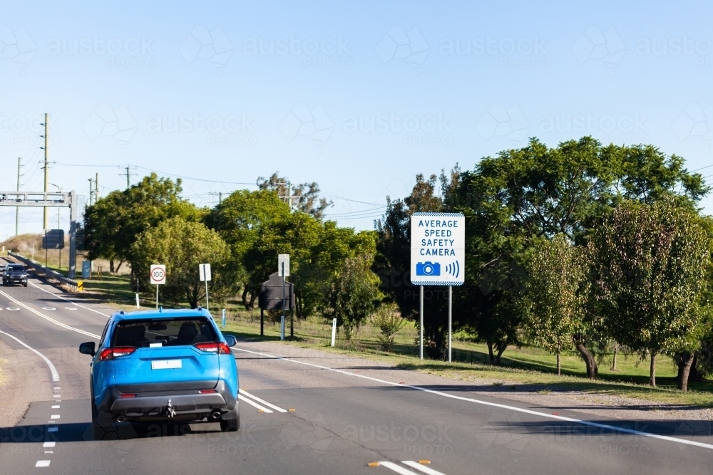 Image of Blue car on road driving past average speed camera warning ...