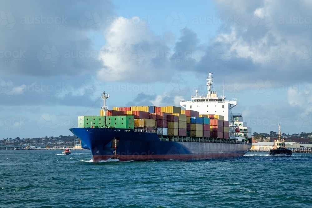 Image of Blue hulled container ship departing port. - Austockphoto