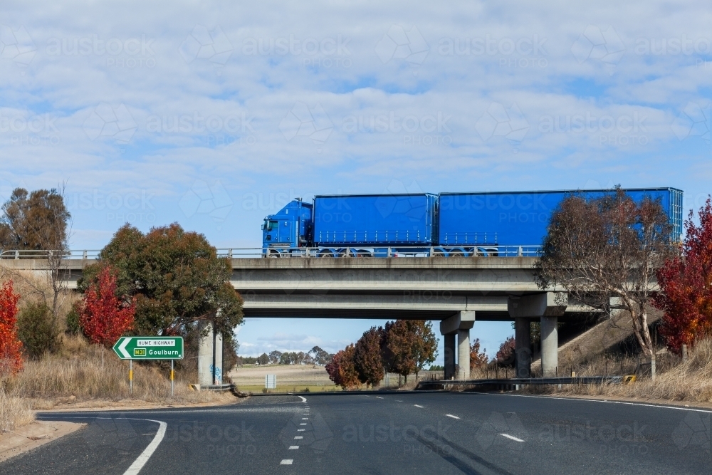 Image of Blue truck passing on overhead overpass bridge with road sign ...