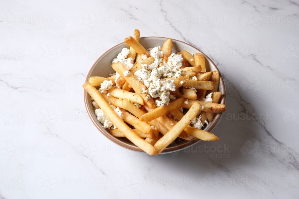 Image of Bowl of hot chips with sprinkled feta cheese - Austockphoto