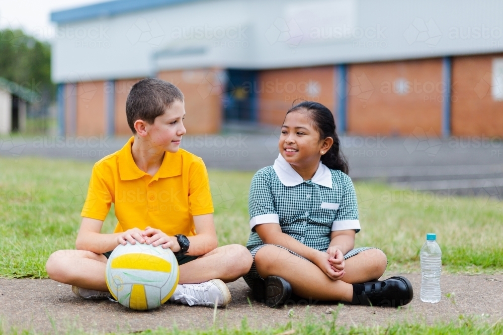 Image of Boy and girl student at Primary school sitting on the ground ...