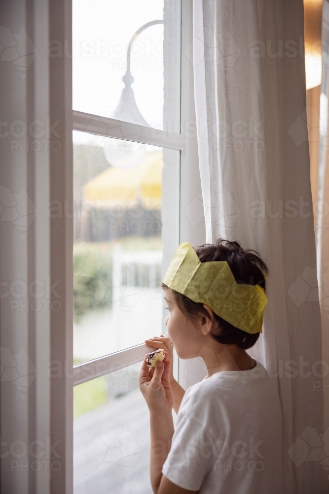 Image of Boy at window wearing a Christmas crown and eating a mince pie ...