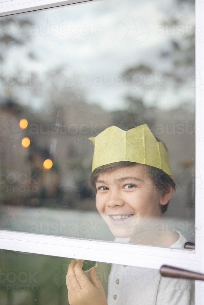 Image of Boy at window wearing a Christmas crown and eating a mince pie ...
