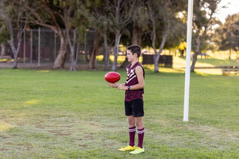Image of boy balancing football on his fingers standing on playing ...