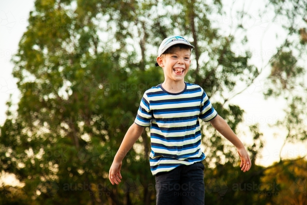 Image of Boy being silly standing on fence post - Austockphoto