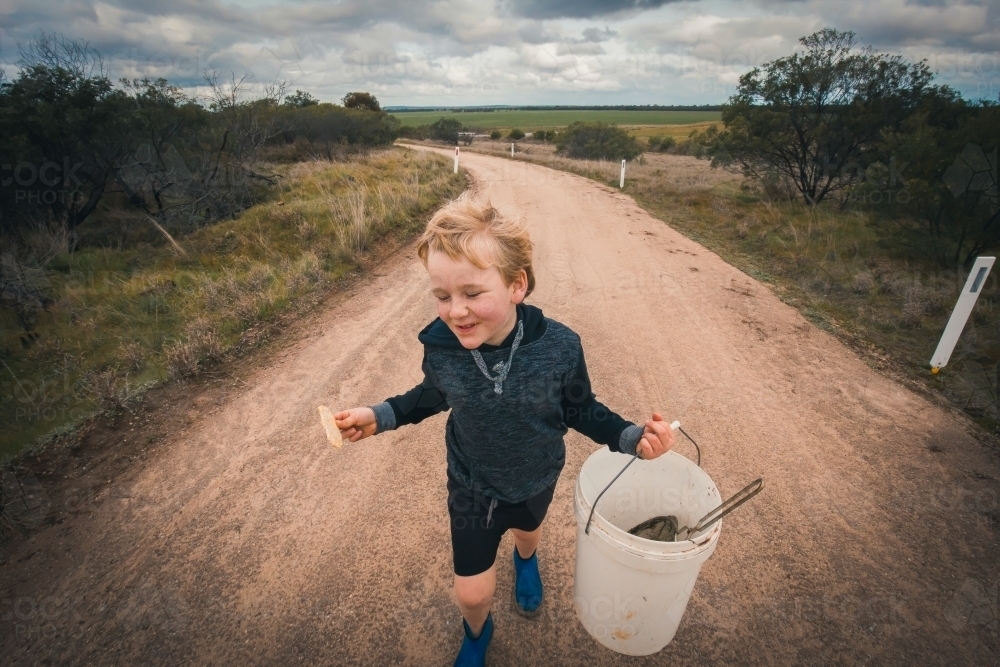Image of Boy carrying bucket and net walking along country lane on ...