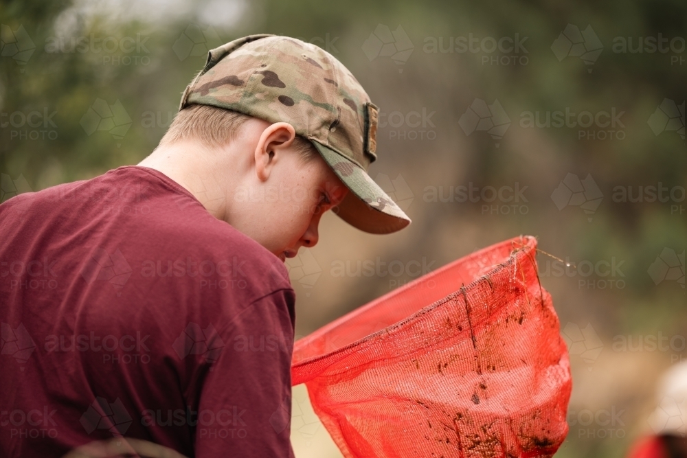 Image of Boy catching tadpoles. Outdoor nature activity. - Austockphoto