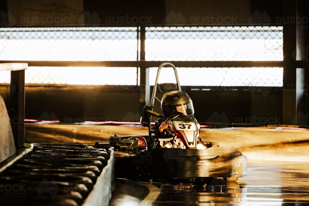Image of Boy driving Go Kart on indoor race track circuit - Austockphoto
