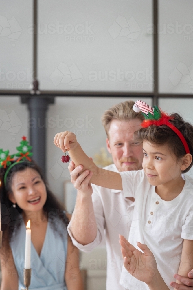 Image of Boy holding cherry with help of parents - Austockphoto
