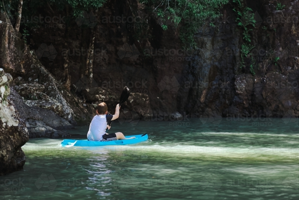 Image of Boy paddling kayak at Cedar Creek Falls in the Whitsundays ...