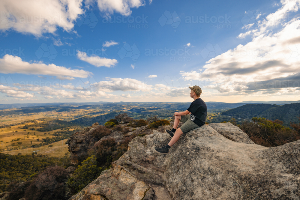 Image of Boy sitting on rock at Hassans Walls Lookout watching valley ...