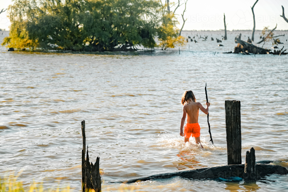 Image of Boy standing in shallow water with long stick at Kow Swamp in ...