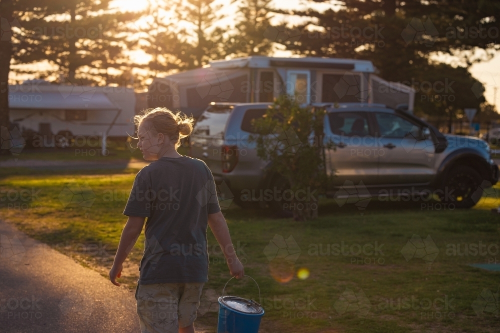 Image of Boy walking through caravan park in golden afternoon light ...