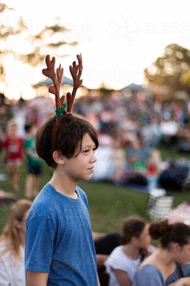 Image of boy wearing antlers at the carols with his family - Austockphoto