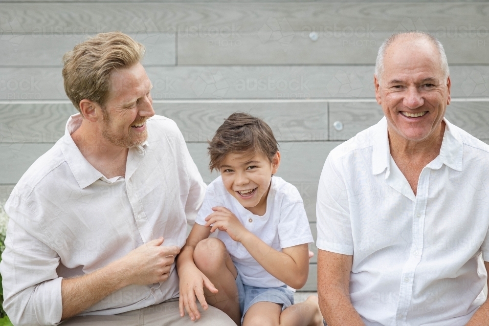 Image of Boy with father and grandfather sitting on outdoor stairs ...