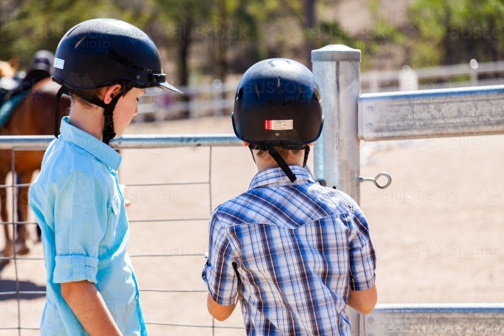 Image of Boys opening gate to riding school paddock - Austockphoto