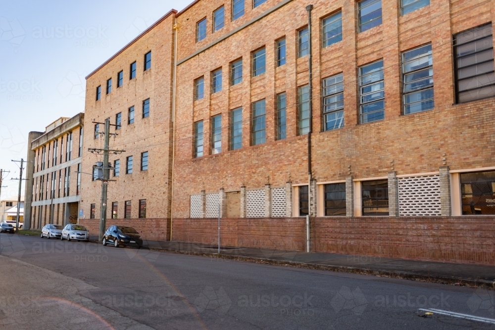 Image of brick building full of windows beside street with cars parked ...