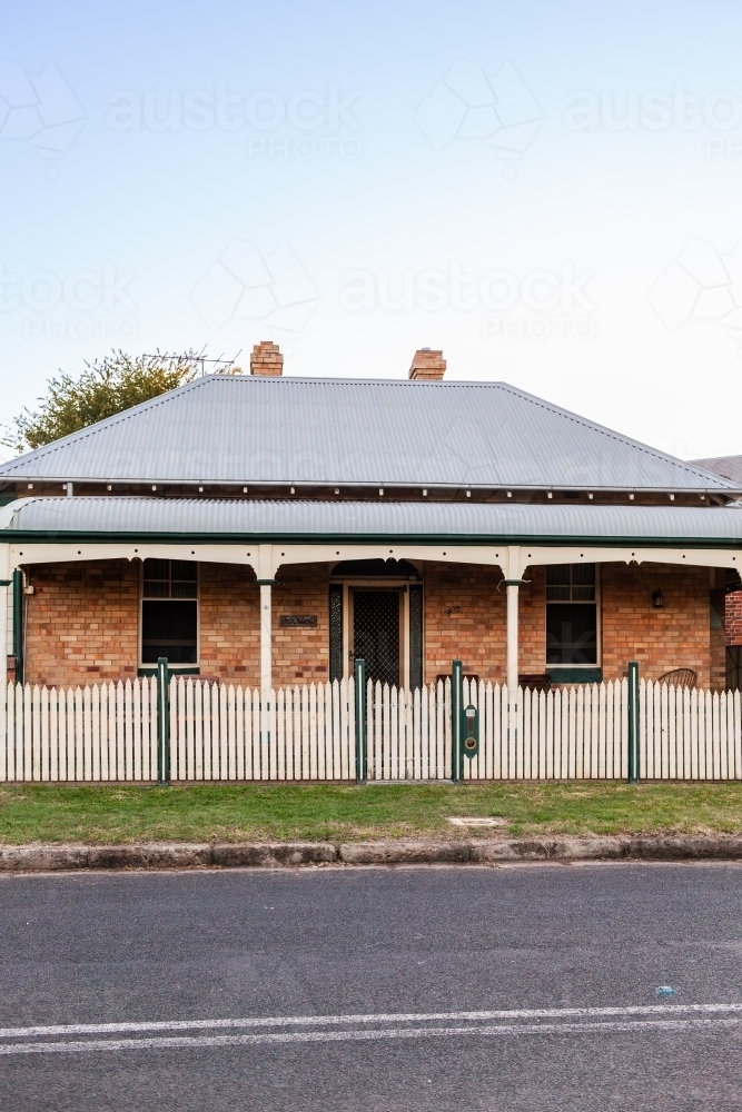 Image of Brick house with picket fence in evening light - Austockphoto