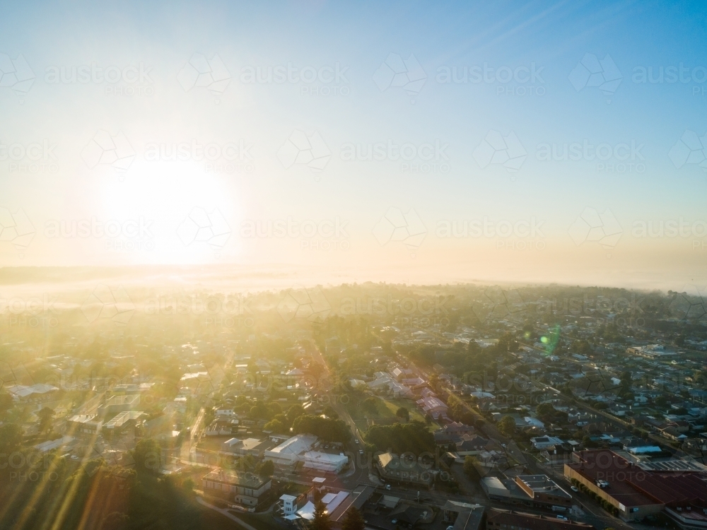 Image of Bright sun flare over quiet country town surrounded by mist on ...
