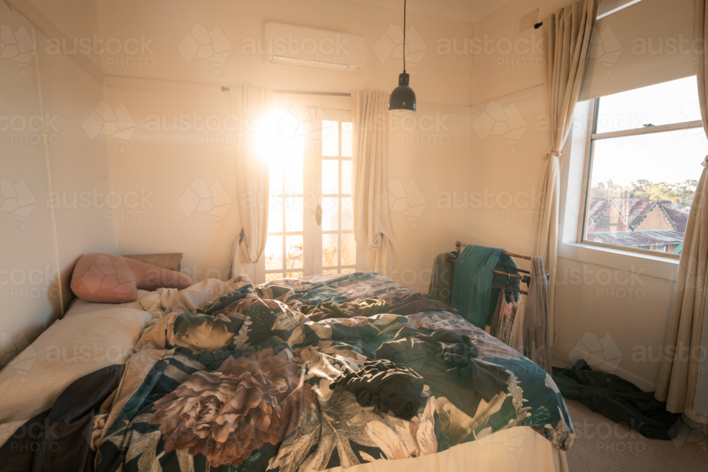 Image of Bright sunlight entering messy bedroom through french door ...