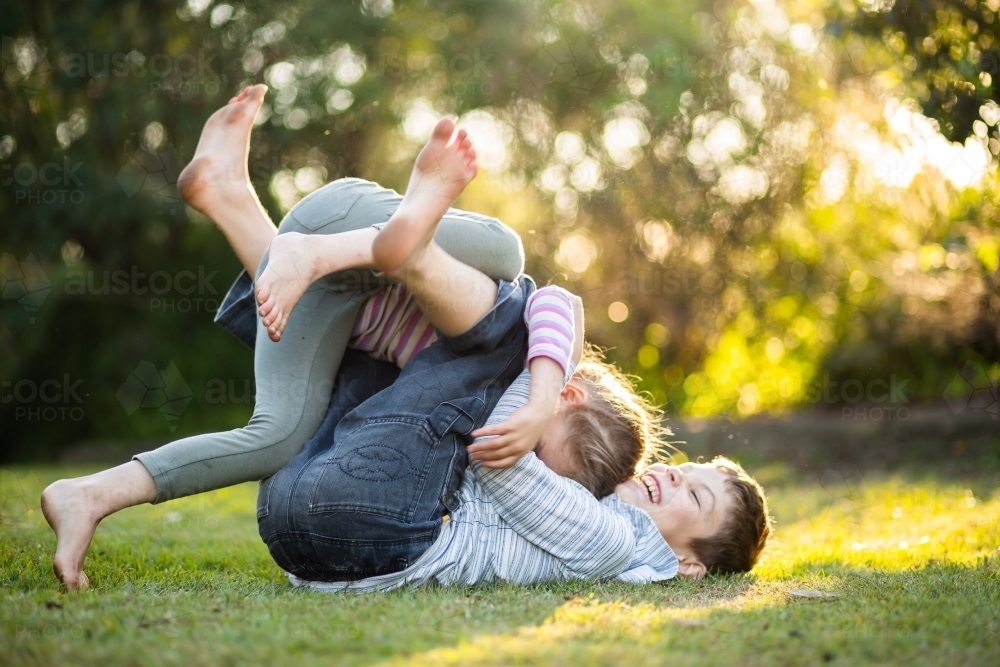 Image of Brother and sister play fighting together on lawn in garden ...