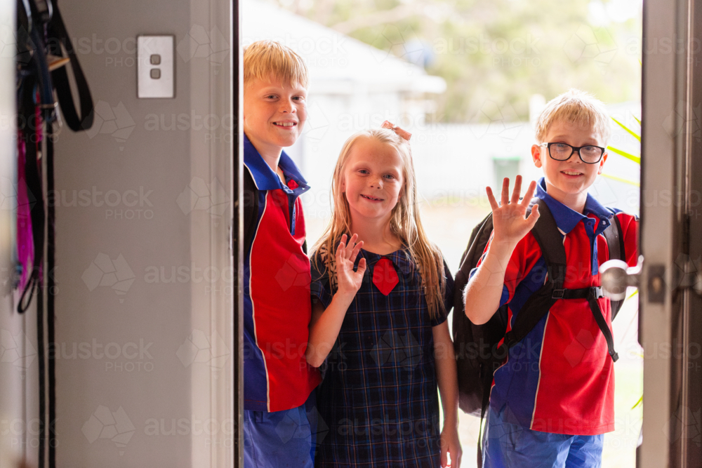 Image of Brothers and sister waving goodbye in doorway before leaving ...