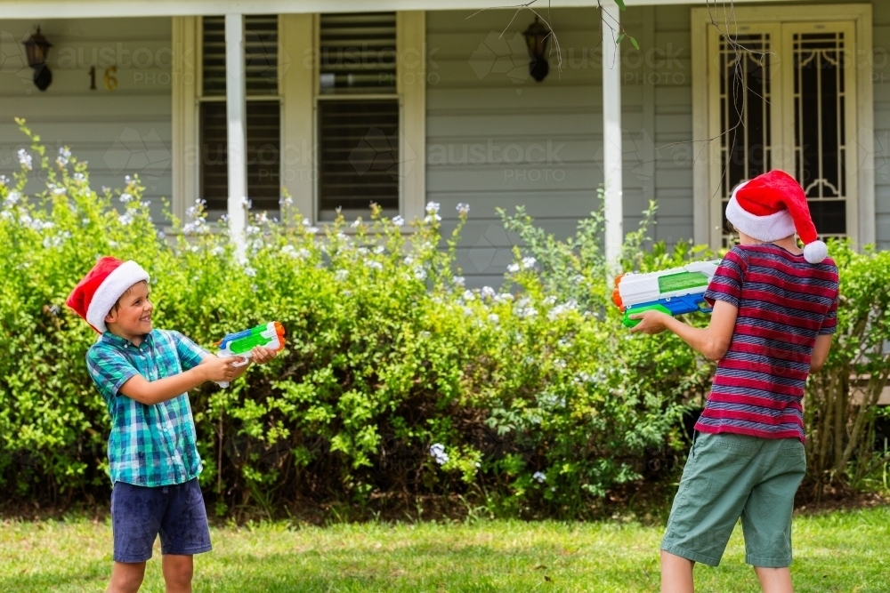 Image of Brothers pointing blaster pistols in Christmastime water fight ...