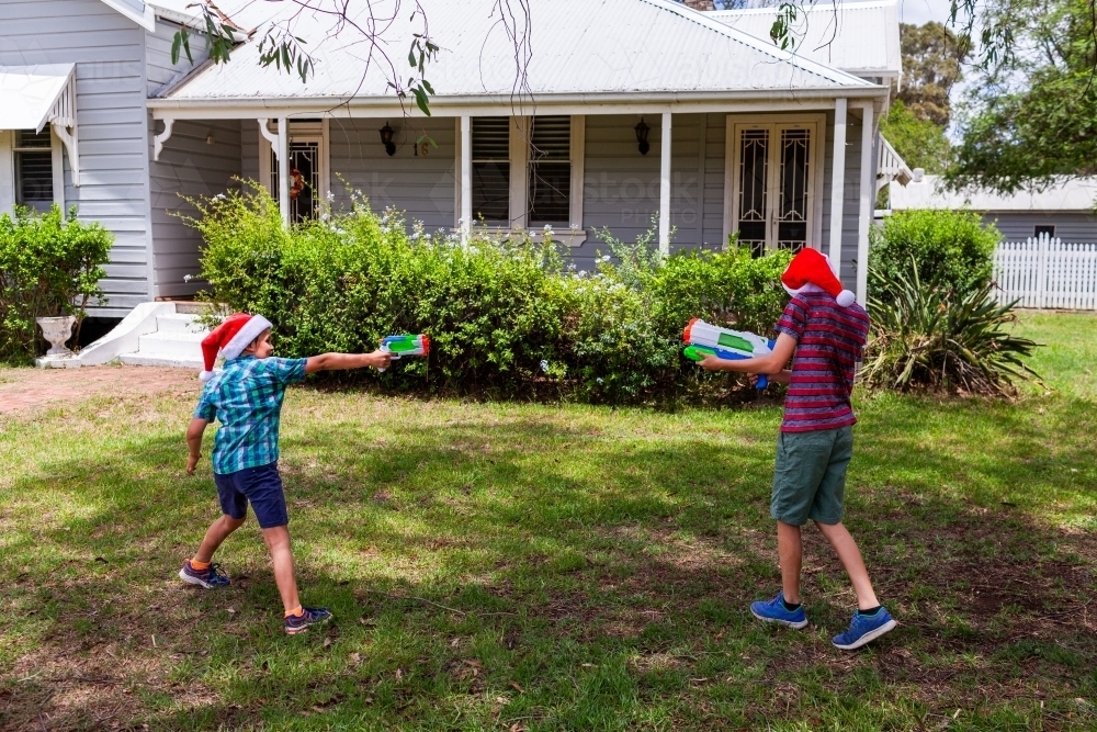 Image of Brothers pointing blaster pistols in Christmastime water fight ...