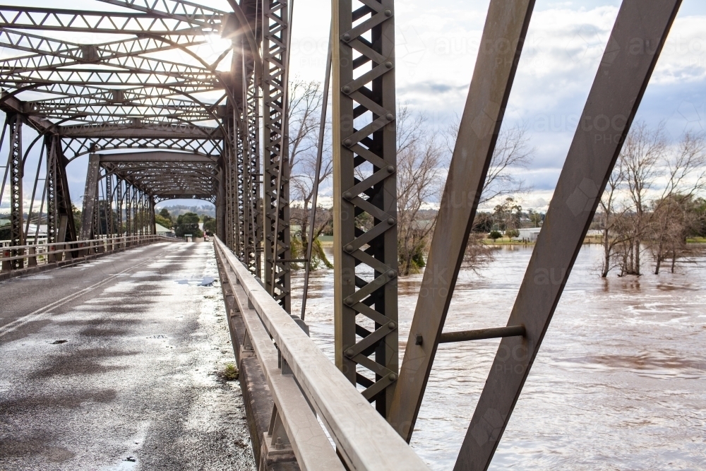 Image of Brown floodwater seen through metal supports of old bridge ...