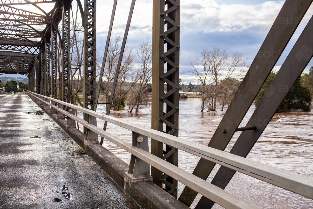 Image of Brown floodwater seen through metal supports of old bridge ...