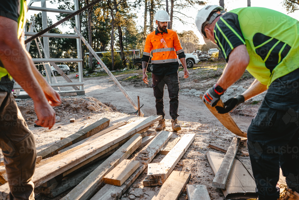 Image of Builders sorting and checking wooden planks on the ground ...