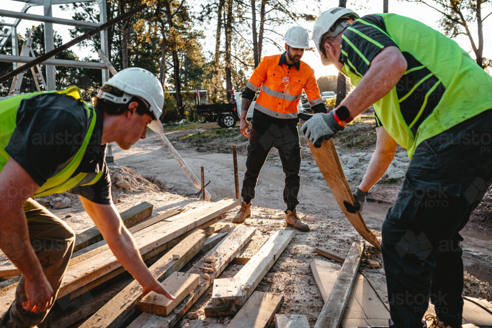 Image of Builders sorting and checking wooden planks on the ground ...