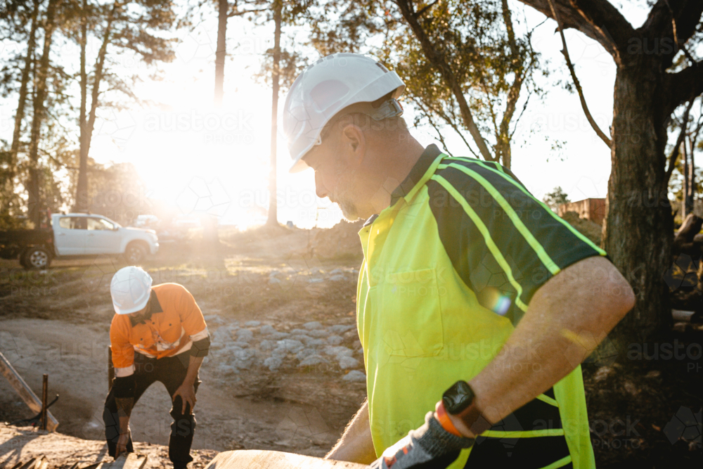 Image of Builders sorting and checking wooden planks on the ground ...