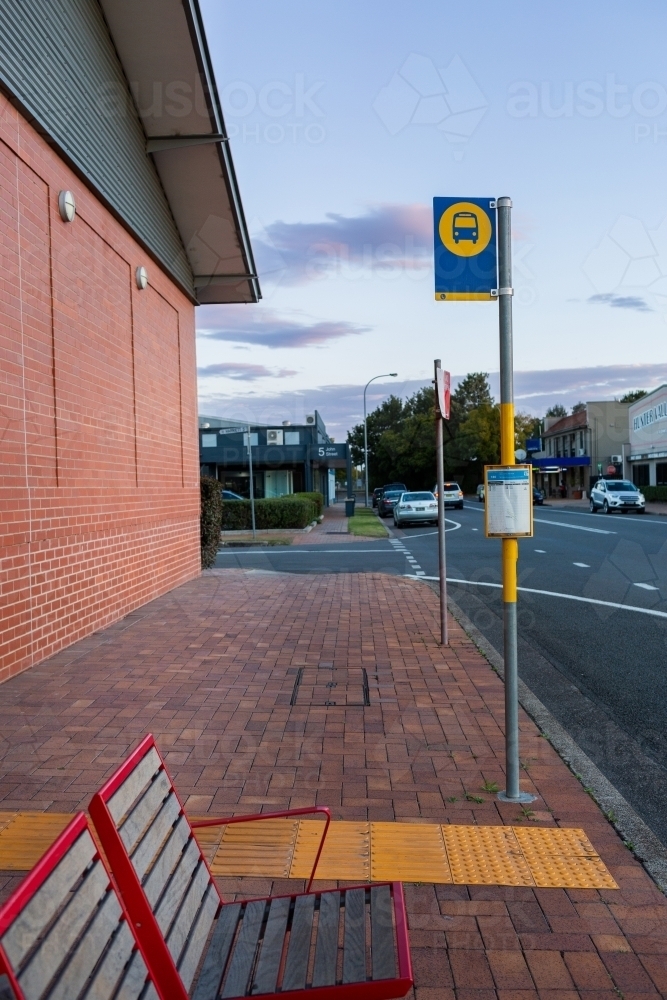 Image of Bus stop sign alongside street at dusk - Austockphoto