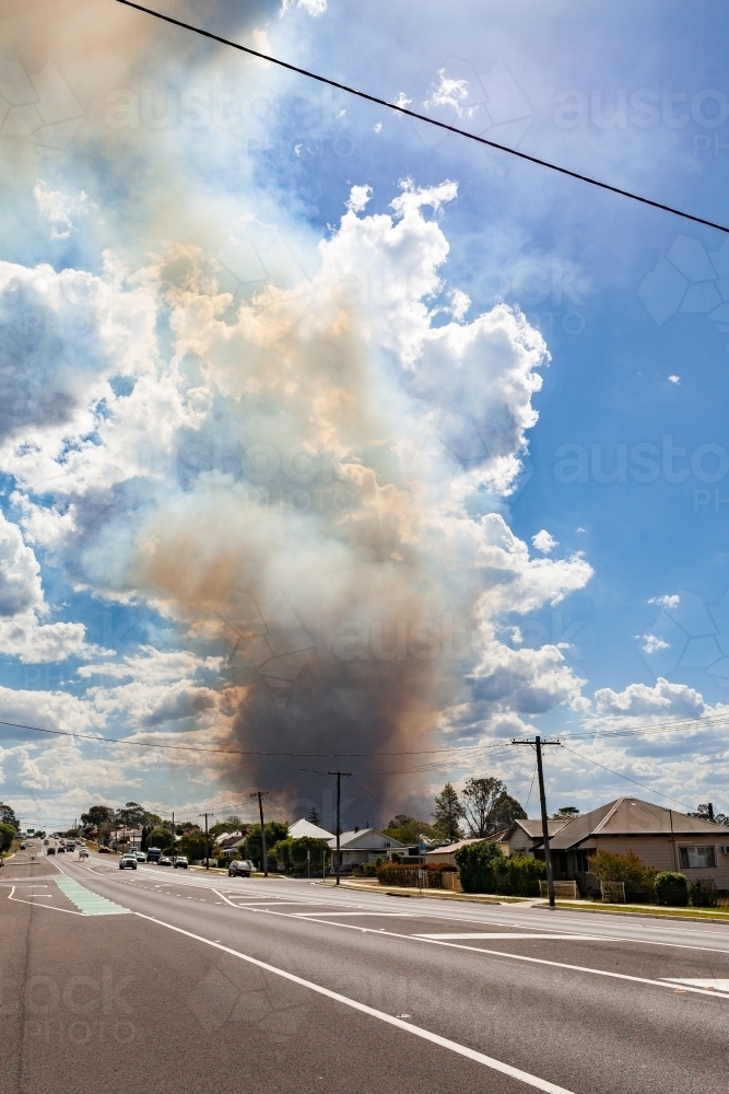 Image of Bushfire smoke billowing into sky behind houses along main ...